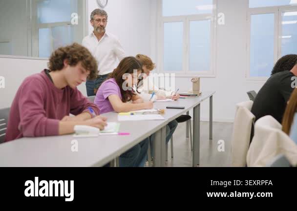 High school professor walking between desks and watching students while ...