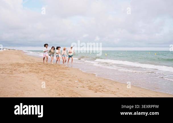 Young multicultural friends having fun, laughing, and running barefoot ...
