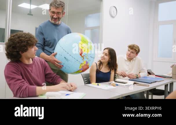 Middle aged professor teaching a geography lesson to a group of high ...