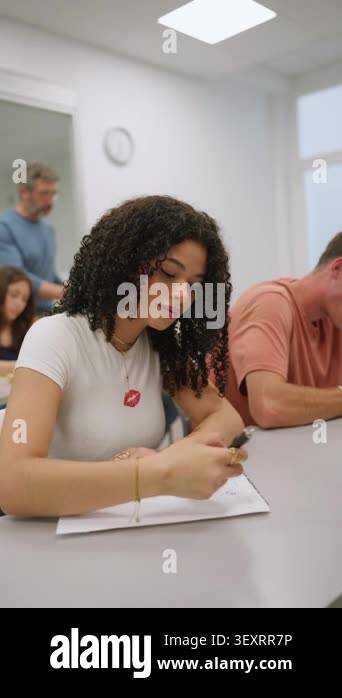 Young female student with curly hair concentrating and writing in her ...