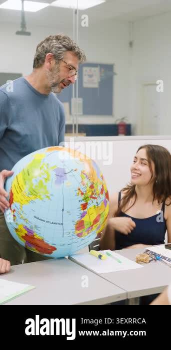 Male teacher using an inflatable globe to teach geography to his ...