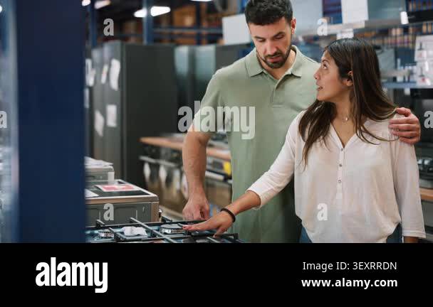 Young happy couple examining a new gas stove in a home appliance store ...
