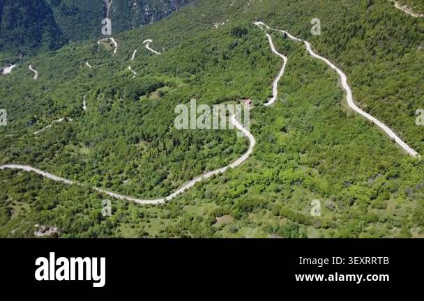 Aerial wide angle view focused on a winding dirt road crossing a lush ...