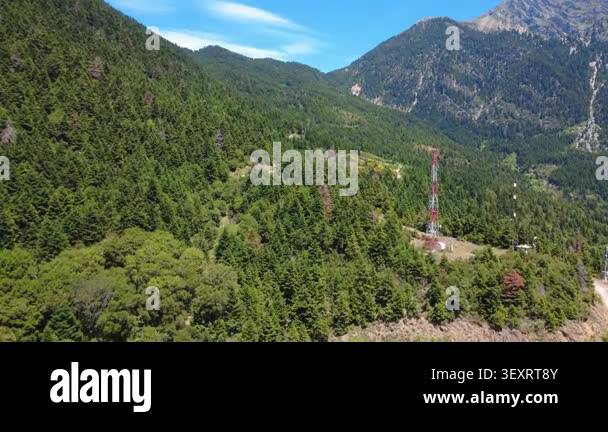 Aerial shot of a relay antenna overlooking mountainous terrain and ...