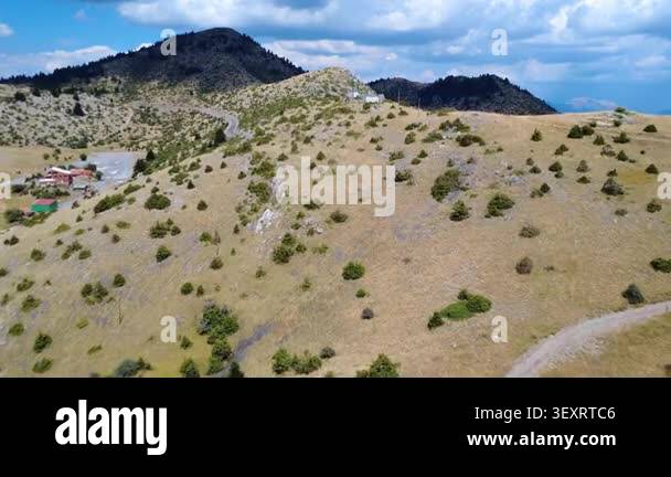 A mountain station with antennas overlooks a valley of dry vegetation ...