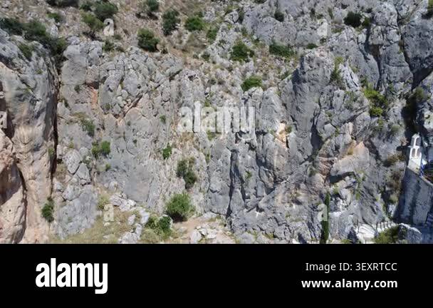 Aerial shot of a chapel sheltered within a rocky cave along a canyon ...