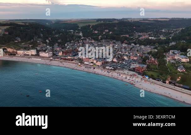 Gentle evening light over Etretat France. The busy beach curves along ...