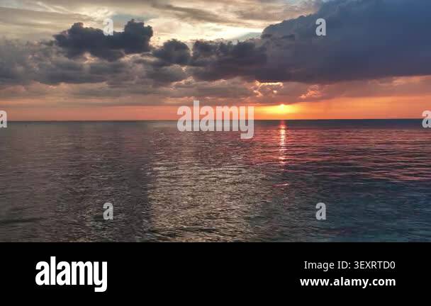 Golden light from the setting sun reflects on the calm ocean surface at ...