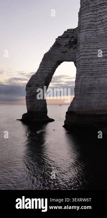 Morning light illuminates the iconic chalk arches and cliffs of Etretat ...