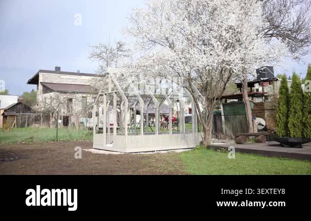 Light painted wooden frame greenhouse with tempered glass sits on ...