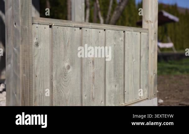 Close up pan across weathered vertical wooden planks with screw heads ...