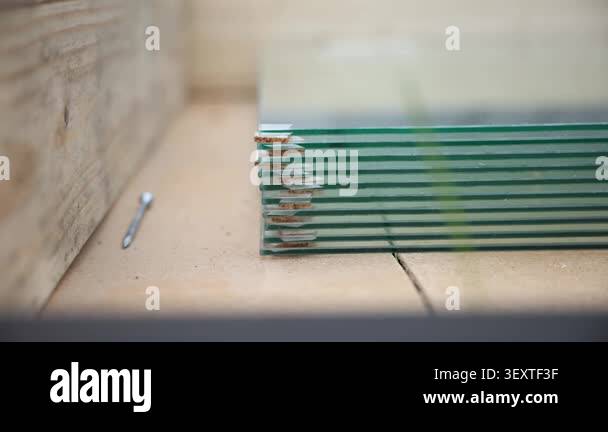Stacked tempered glass panels rest on wooden floor by a timber wall ...