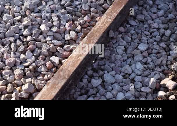 Single rusted rail lies diagonally on crushed stone ballast. Camera ...