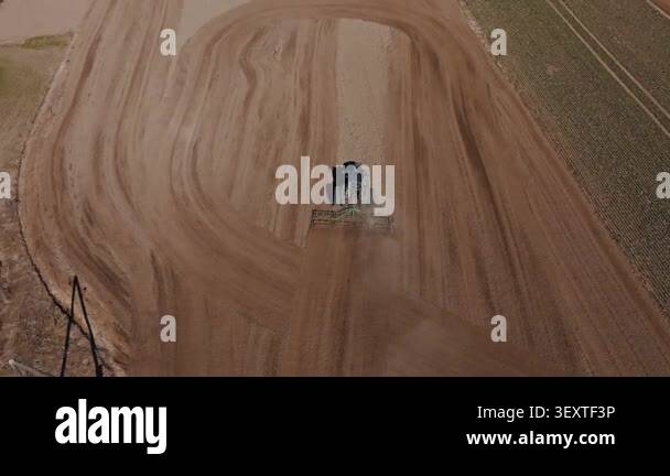 Title Aerial tractor with harrow carves curved tracks on plowed field ...