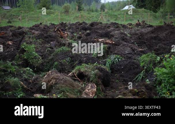 Rough field of turned turf and exposed soil fills the frame. Wire fence ...