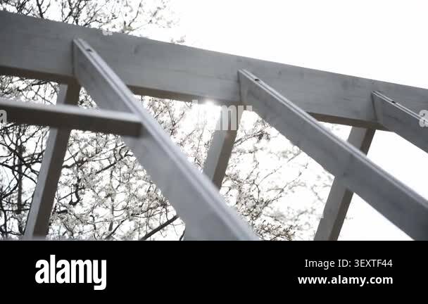 Close up shows painted timber rafters and vertical supports forming a ...