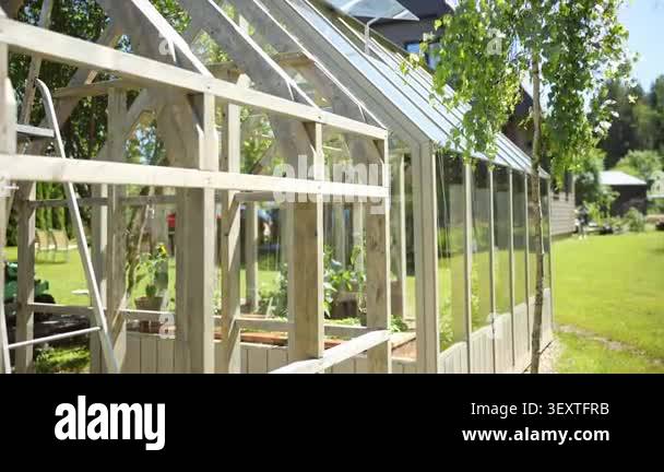 Wooden frame with tempered glass panels stands in a yard as camera ...