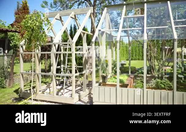 Two adjacent wooden frame greenhouses show glass panels, raised beds ...
