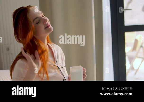Close up portrait of a beautiful young redhead woman holding a coffee ...