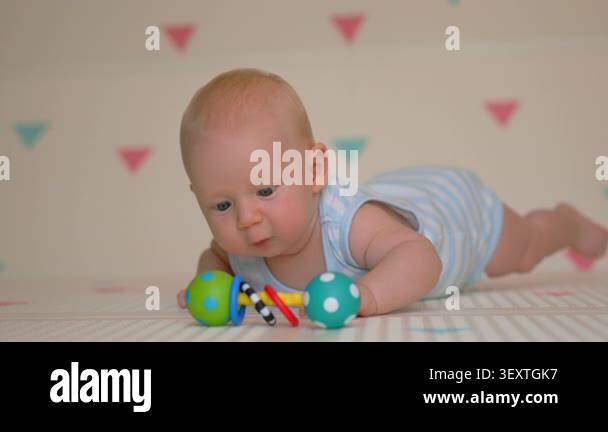 Three month old baby boy lies on the floor at home, actively moving his ...
