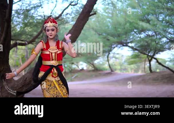 Female performer in ornate red and gold costume holds graceful dance ...