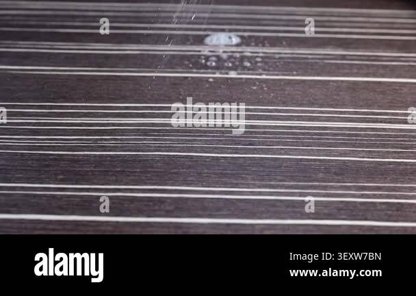 a foamy liquid cleaner being sprayed onto a dark wooden surface with a ...