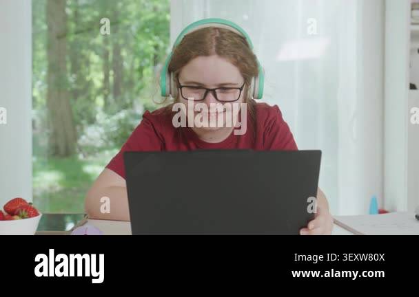 Learning at desk with laptop. Child learning wears wireless headphones ...
