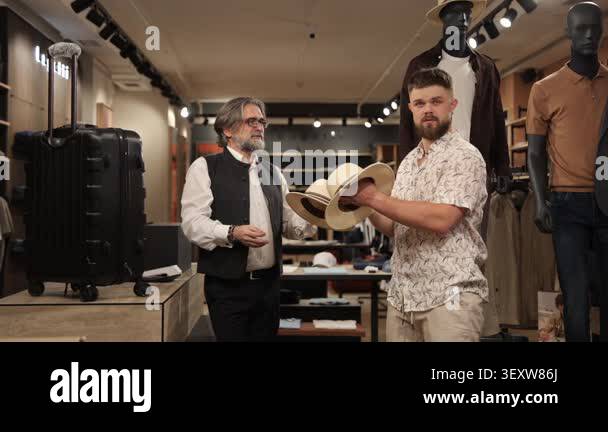 Helpful shop assistant advising a male customer trying on a stylish ...