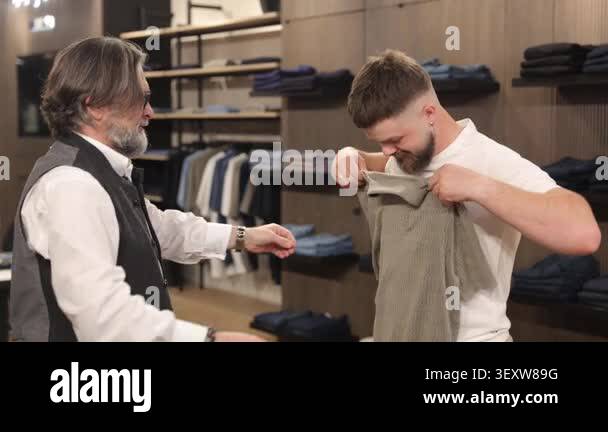 Young male customer choosing a polo shirt with the help of an ...