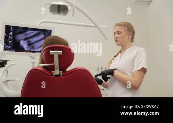 Professional female dentist showing a teeth x-ray on the screen and ...