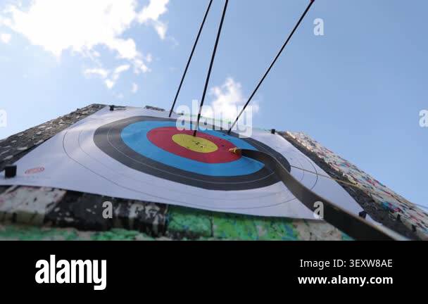 Multiple arrows hitting the center of a paper target during an archery ...