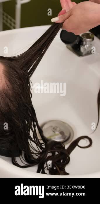 Professional hairdresser applying conditioner or mask to a clients wet ...