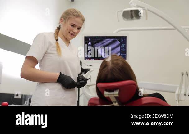 Professional woman dentist showing an x-ray on the screen to her ...