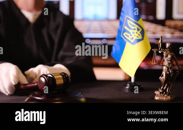 Judge hitting a gavel in court with the ukrainian flag and a statue of ...