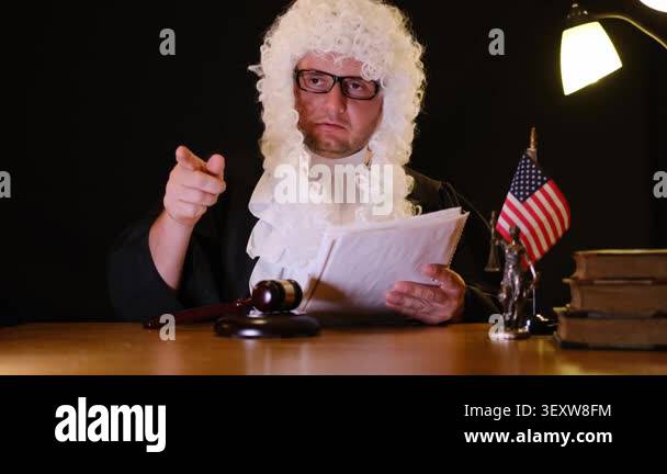 Man in a judges costume with a powdered wig reading a document and ...