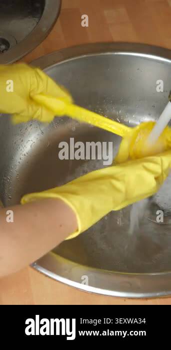 Hand in rubber glove washing cleaning brush under flowing water stream ...