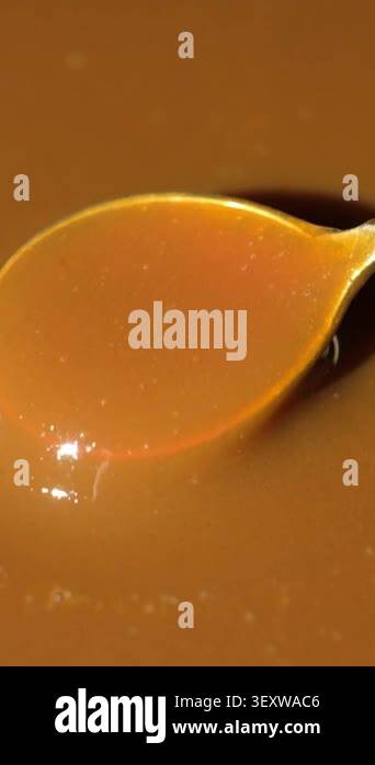 Liquid caramel sauce dripping from spoon vertical slow motion Stock ...