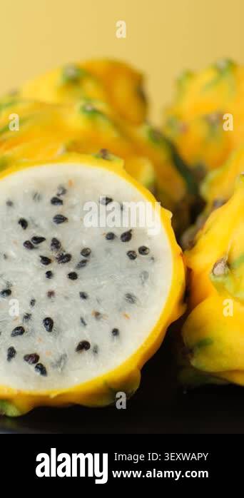 Halved yellow dragon fruit showing white flesh and black seeds Stock ...