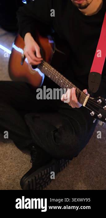 Young handsome talented guitarist in glasses playing guitar in studio ...