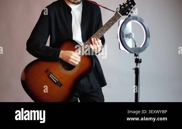 Young musician guitar teacher recording video lesson on phone with ring ...