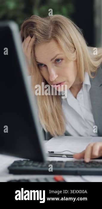 Woman leans on hand while looking at computer screen in a modern office ...