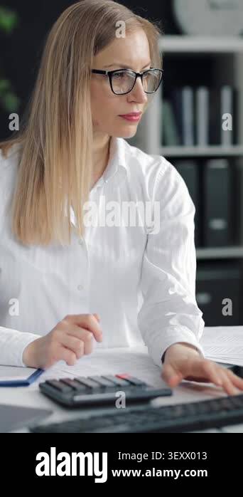 Woman in office works on documents and calculator during the day Stock ...