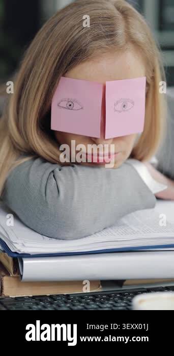 Candid shot of a woman resting her head on her arms at an office desk ...