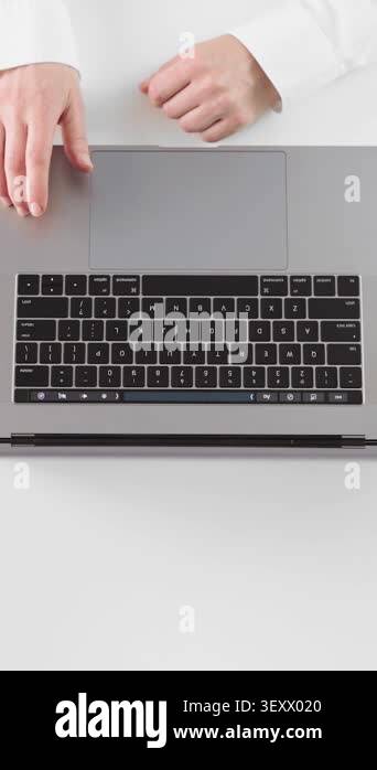 Close view of hands typing on a laptop keyboard in a bright workspace ...