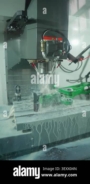 Milling machine processing metal parts with coolant spray demonstrates ...