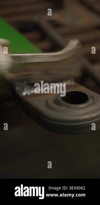 Worker polishing a metal part with a wire brush in an industrial ...