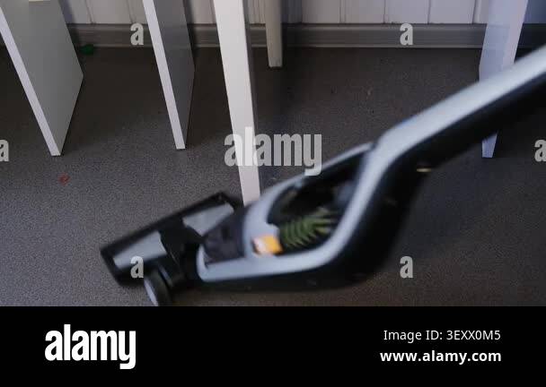 vacuum cleaner to clean the floor underneath furniture in a room. The ...