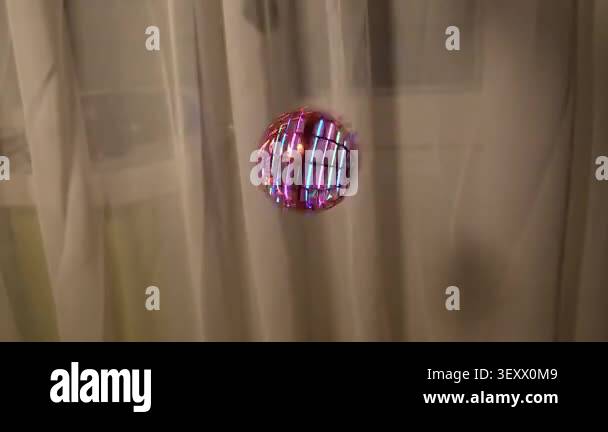 A lighted ball hovers in the air while spinning slowly. Colors change ...