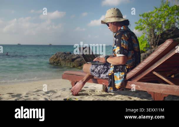 Freelancer Using a Laptop by the Beach During Sunset, Showcasing Remote ...