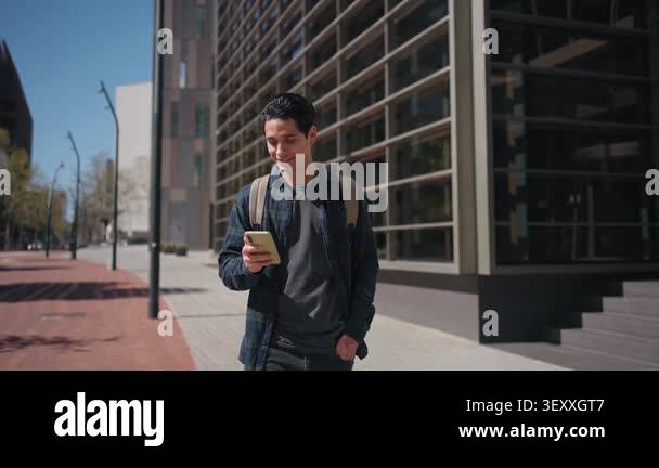 Young hispanic student walking using mobile smartphone app in the city ...